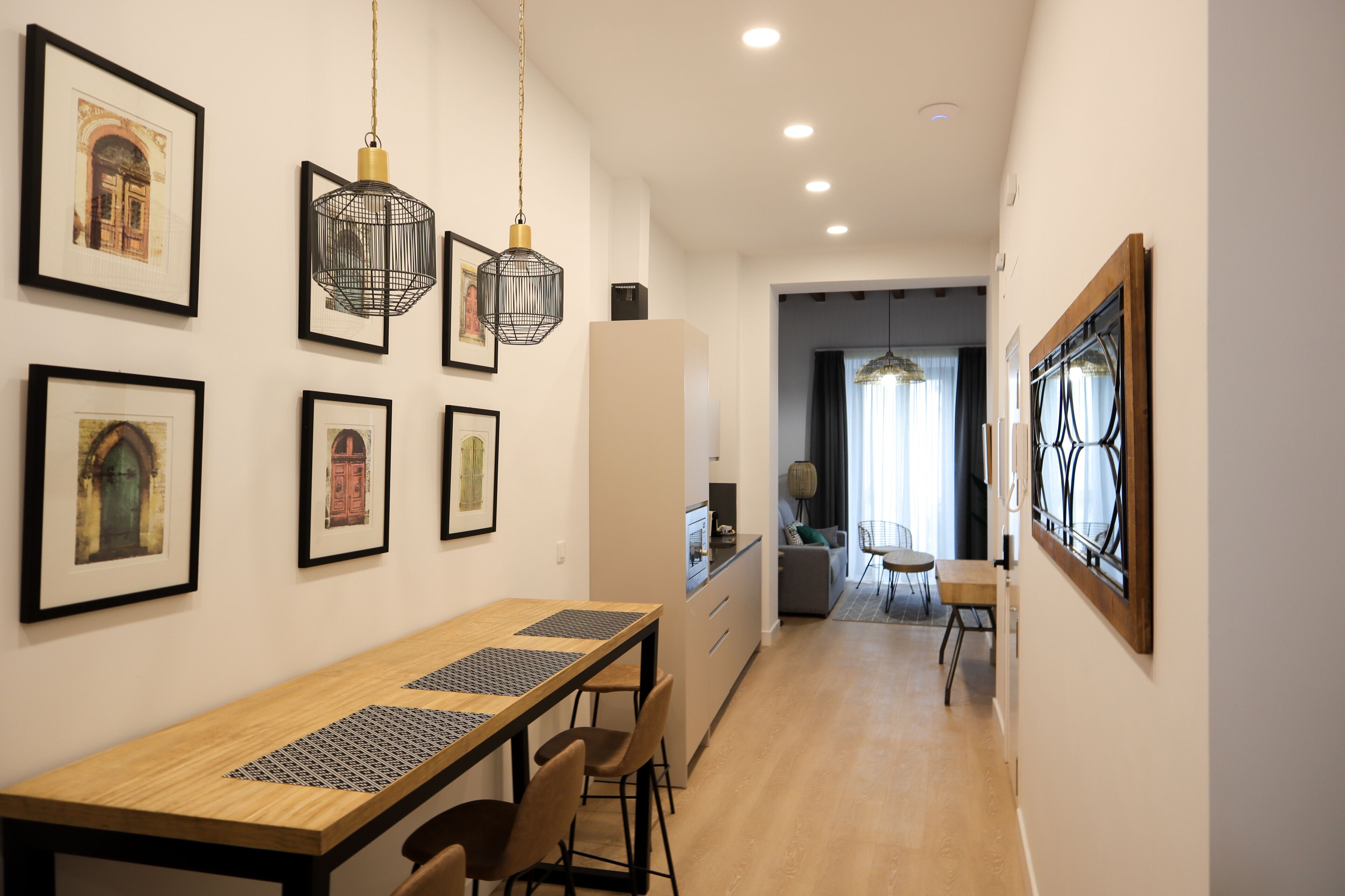 Uma cozinha moderna com ilha de madeira, luminárias pendentes e quadros nas paredes.