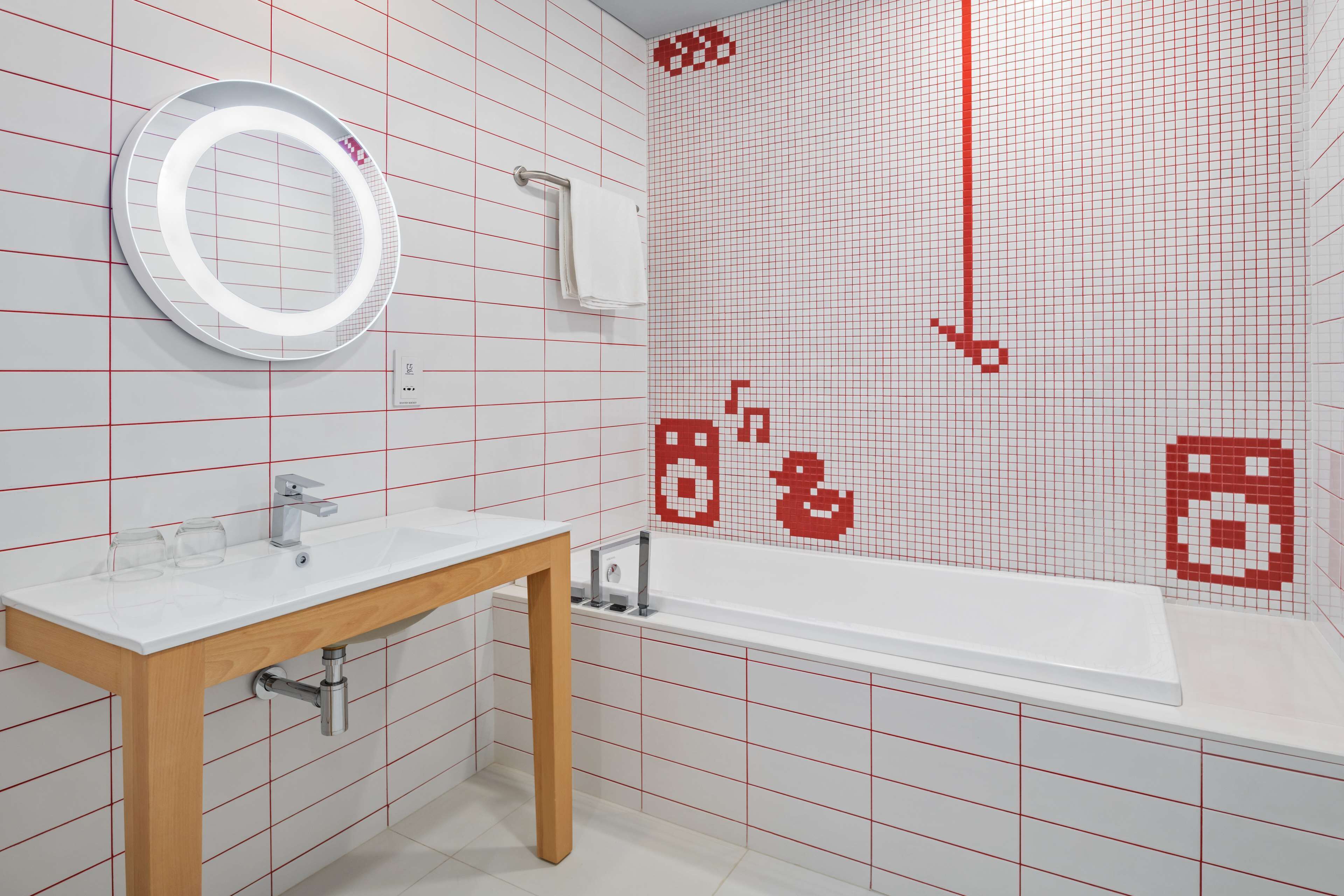 Uma casa de banho moderna com uma pia branca, espelho e banheira.