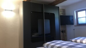 Quarto com cama, guarda-roupa, espelho e janela.
