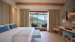 Quarto de hotel com uma cama grande, uma escrivaninha, uma cadeira e vista para o mar.