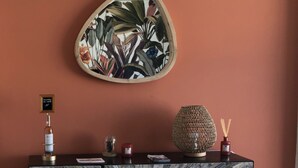 Um armário de madeira com design radial, um espelho decorativo e uma pequena mesa com velas e uma garrafa.