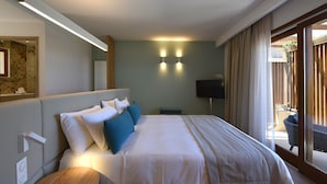 Quarto de hotel com uma cama grande, mesas de cabeceira, televisão de tela plana e vista para a área externa.