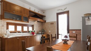 Cozinha moderna com armários de madeira, uma ilha grande e uma área de refeições com mesa e cadeiras.