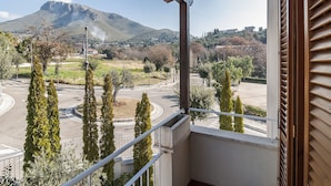 Uma varanda com vista para uma montanha, árvores e uma estrada.