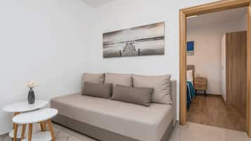 Uma sala de estar moderna com um sofá, uma mesinha e uma pintura de um cais.