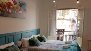 Quarto de hotel com duas camas, um quadro na parede e uma varanda com vista.