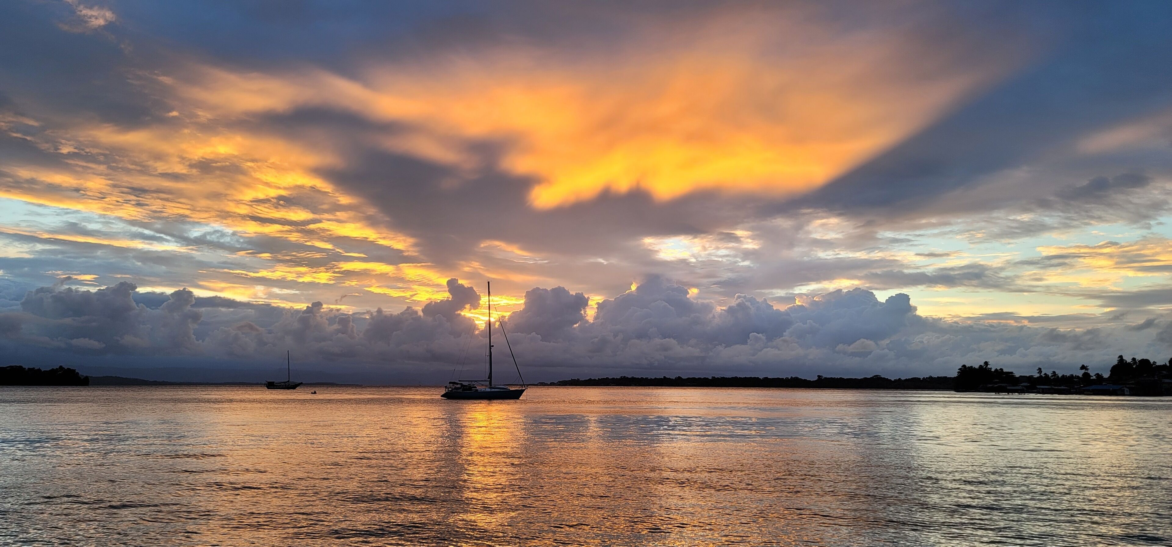 Mar calma com um veleiro e uma costa distante.