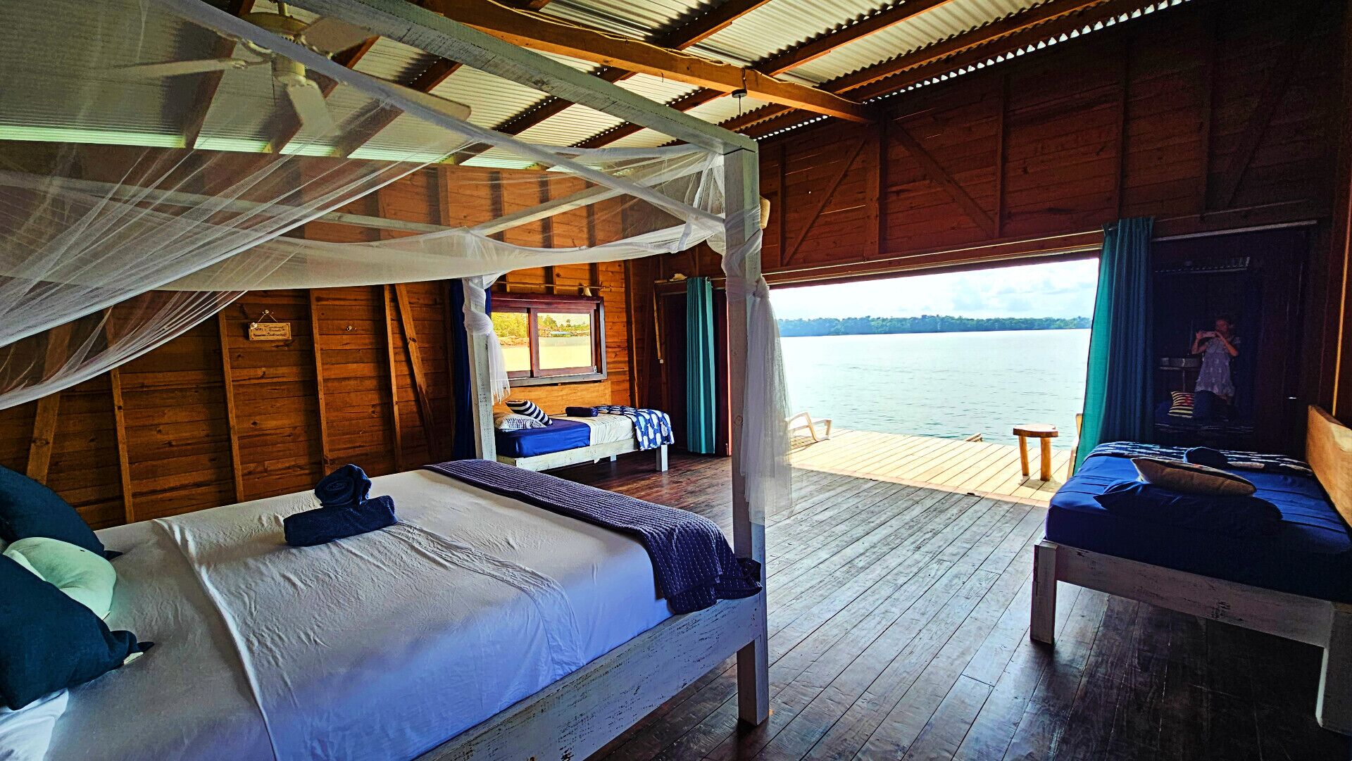 Uma cabana com uma cama, um banco e vista para um lago.