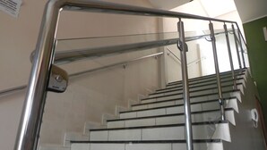 Uma escadaria com corrimãos de metal e azulejos brancos.