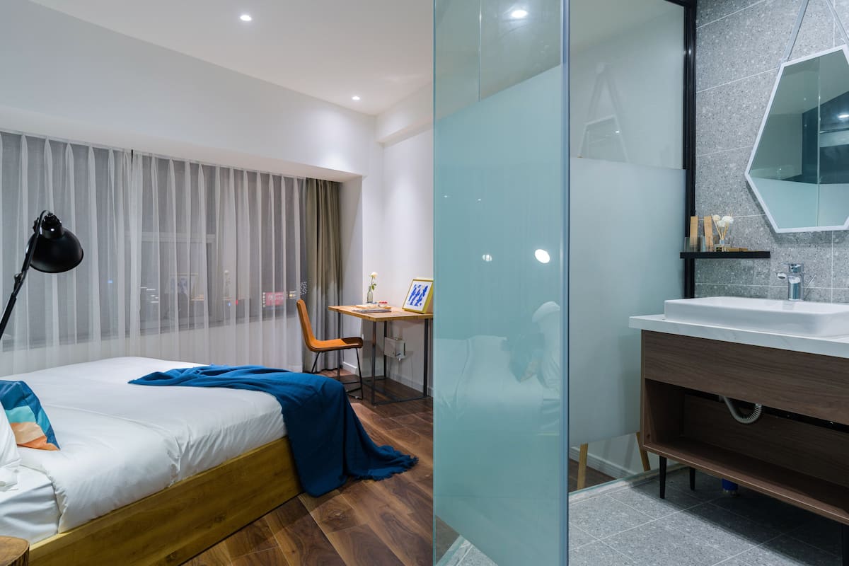 Quarto de hotel moderno com cama, escrivaninha e banheiro.