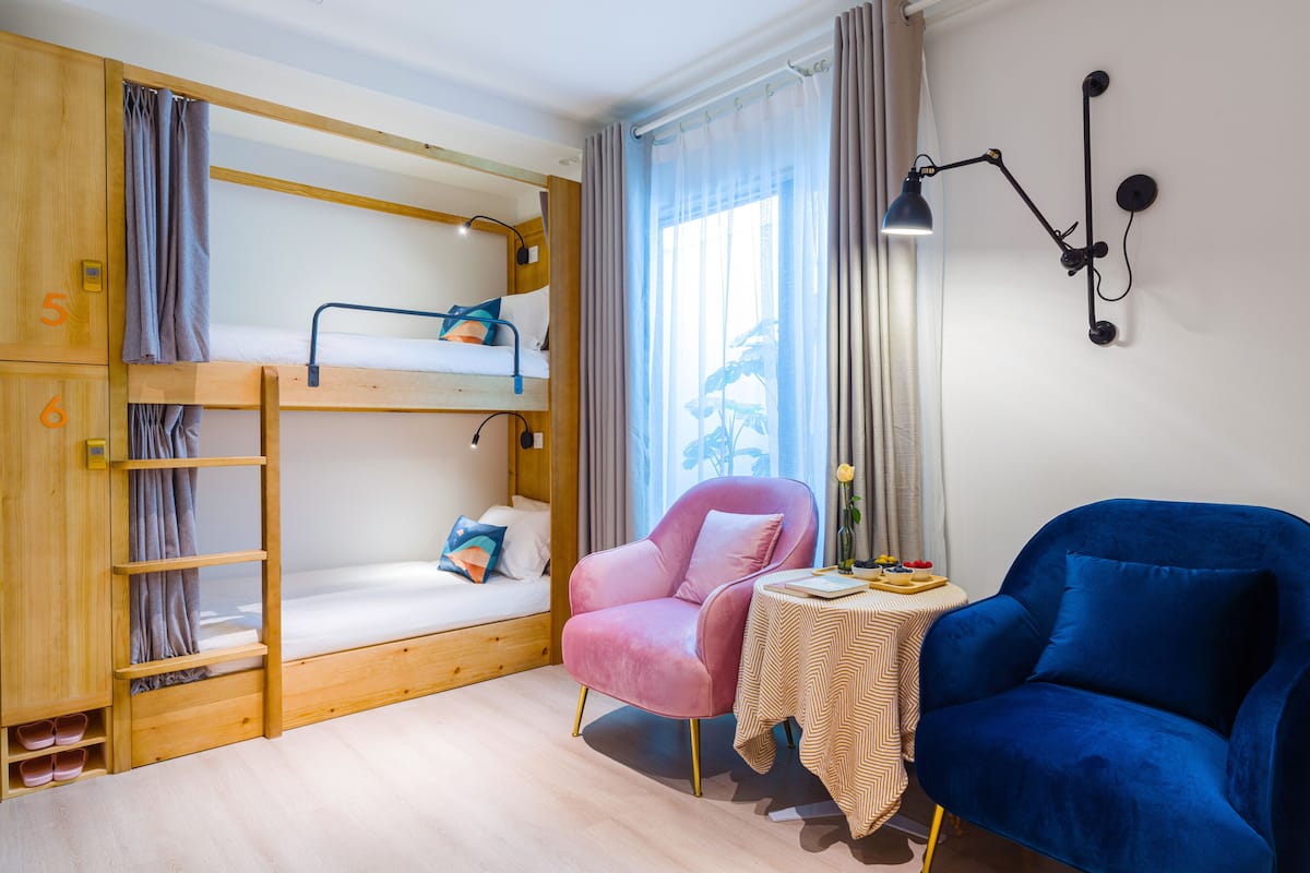 Quarto com beliche, uma cadeira rosa e um sofá azul.