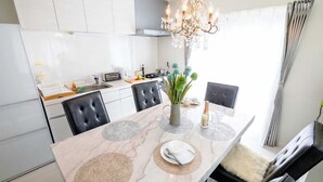 Cozinha moderna com armários brancos, bancada de mármore e lustre.