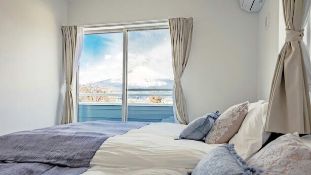 Quarto com uma cama grande, cortinas e vista para uma paisagem nevada através de uma janela.