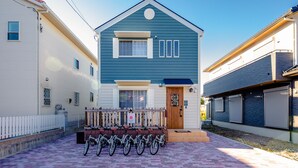 Uma casa de dois andares com fachada azul e cerca branca de piquete.