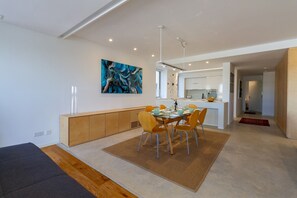 Uma área de refeições moderna com uma mesa posta para quatro pessoas, um armário de madeira e uma grande pintura abstrata na parede.