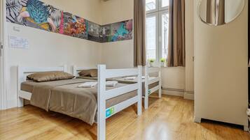 Quarto com duas beliches, janela com cortinas, espelho fixado na parede e radiador.