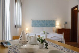 Mesa bem arrumada com bule, xícaras e uma pequena planta em um quarto de hotel.