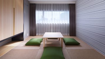 Quarto com piso de tatame, mesa baixa com almofadas e vista através de cortinas leves.
