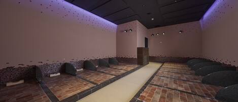 Um espaço de spa com várias áreas de estar, um caminho central e piso ladrilhado.