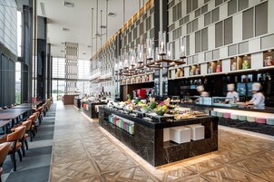 Um restaurante moderno com um balcão extenso, diversas áreas de estar e uma cozinha visível ao fundo.