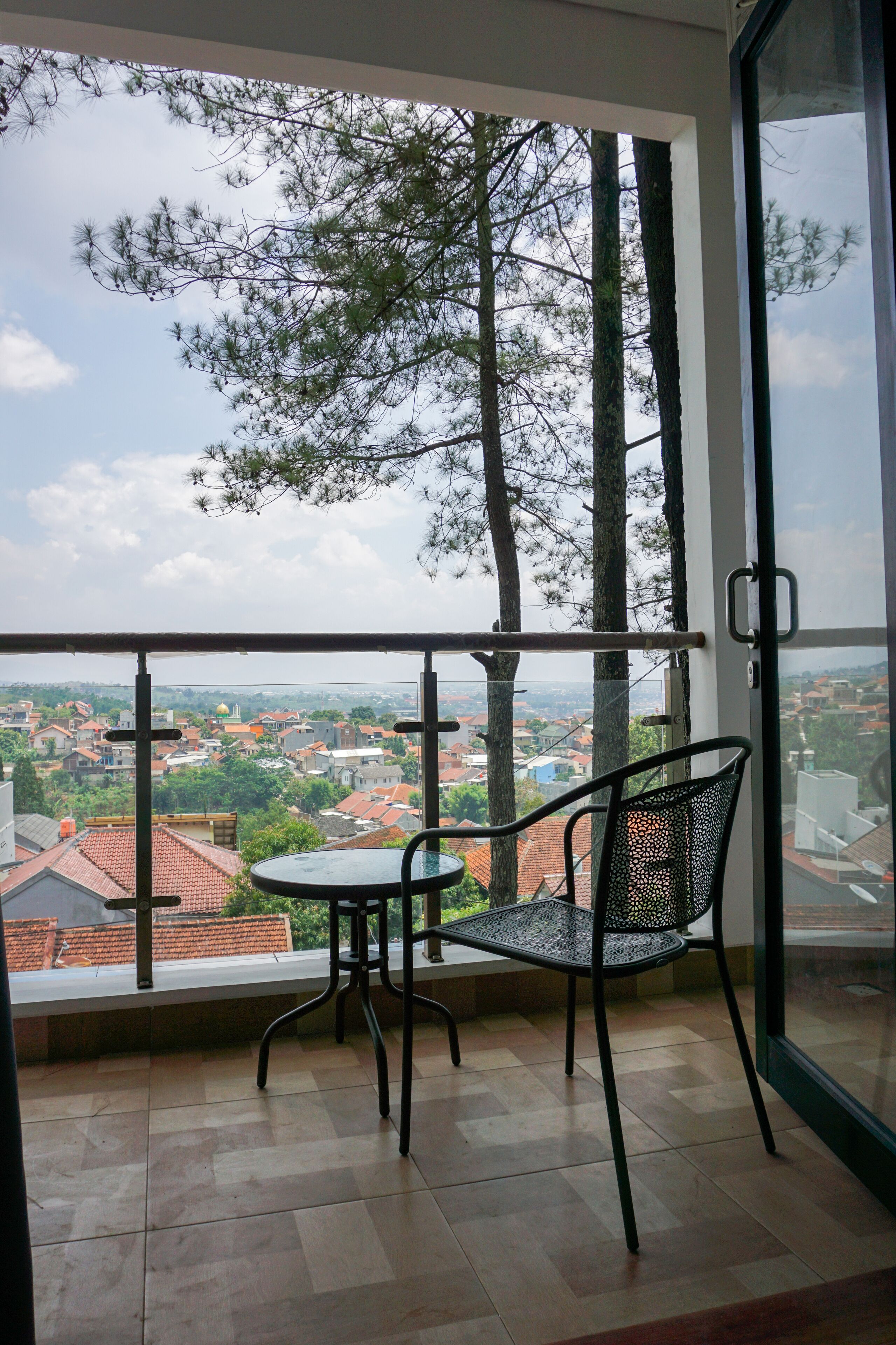 Varanda com mesa e cadeira, vista para paisagem urbana com árvores e edifícios.