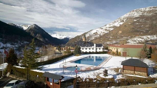 Um resort de montanha com piscina, igreja e montanhas cobertas de neve.
