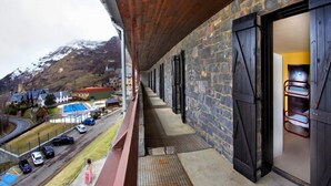 Varanda de hotel com paredes de pedra, piscina e vista para uma área montanhosa.