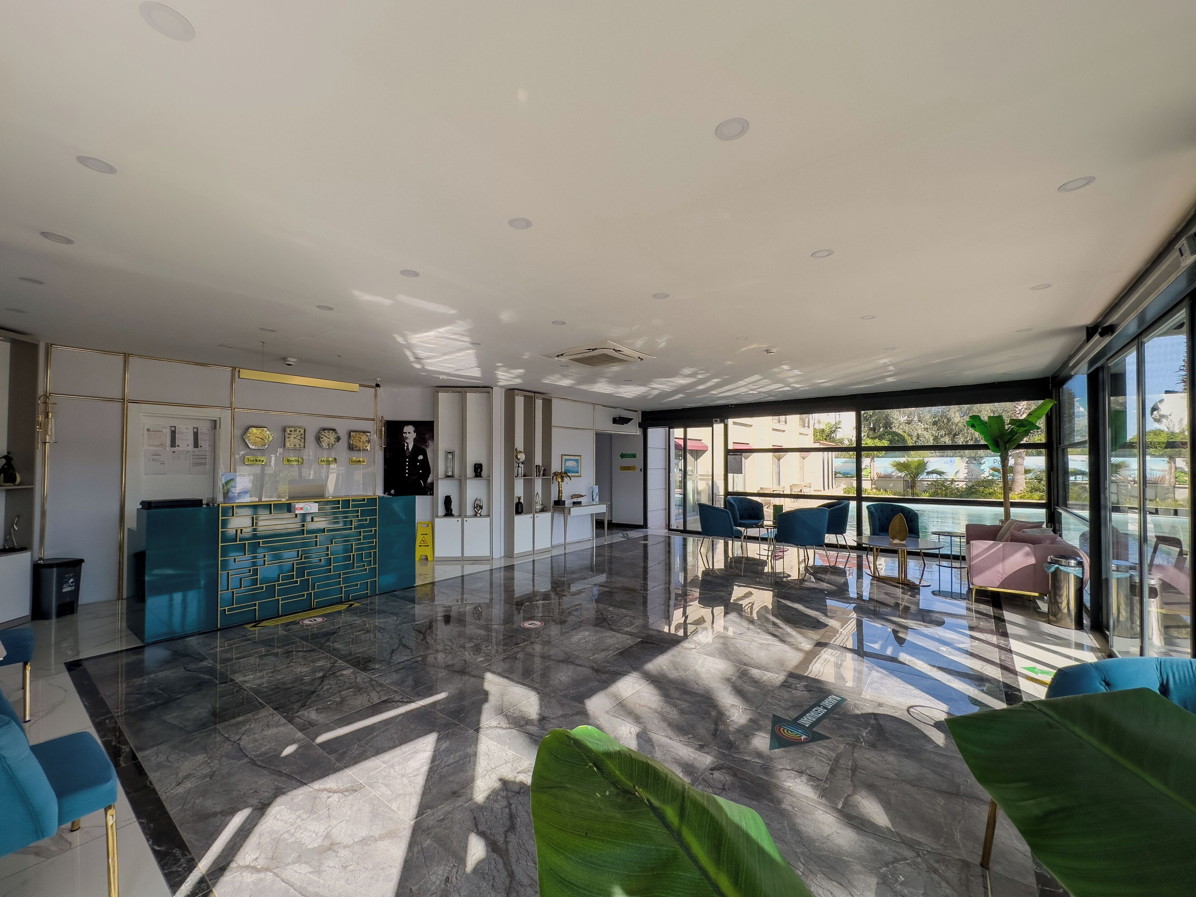 Um lobby moderno com balcão de recepção, área de estar e grandes janelas com vista para o exterior.