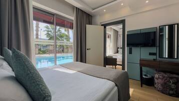 Quarto de hotel com uma cama grande, televisão, escrivaninha e vista para uma piscina.