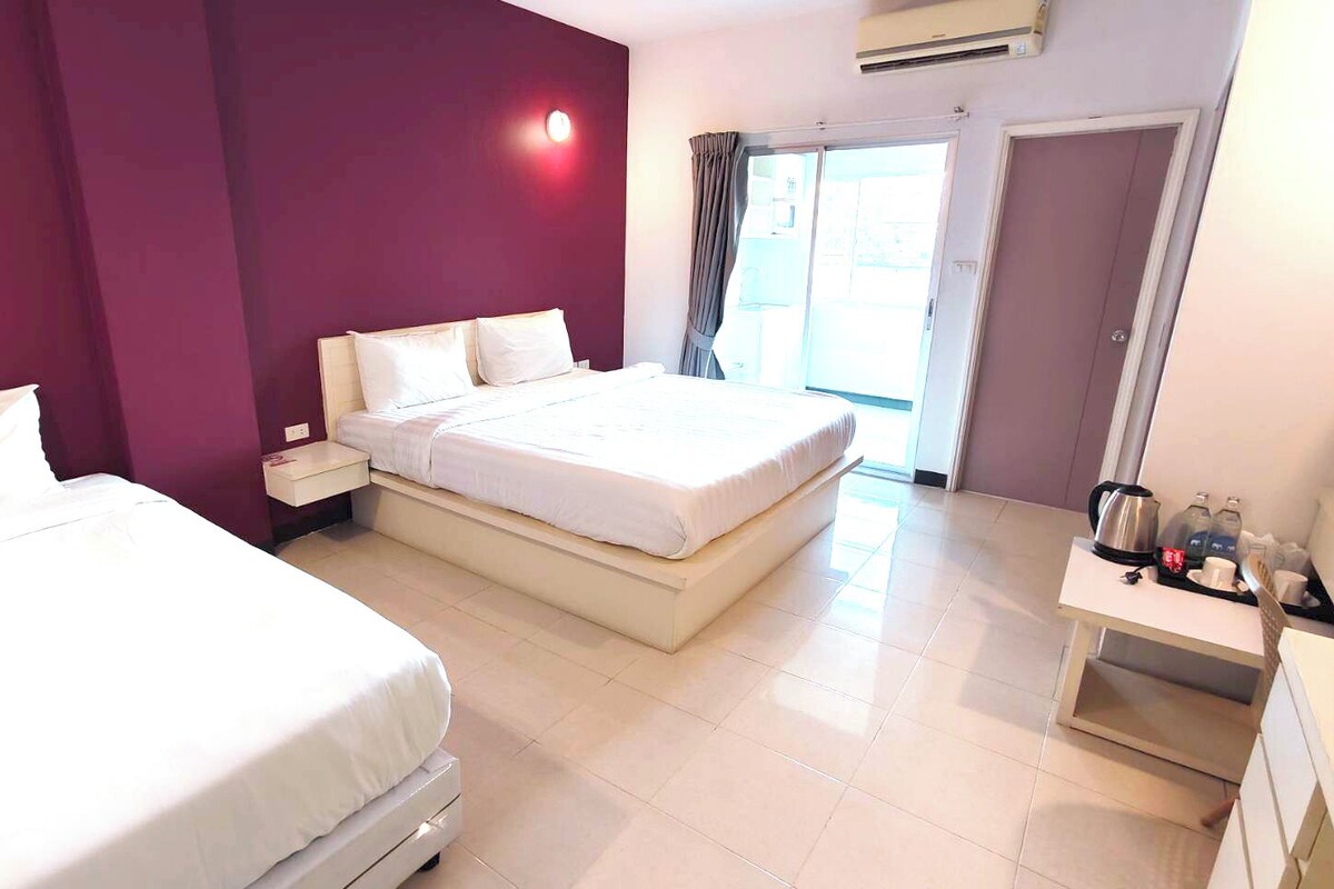 Quarto de hotel com uma cama grande, uma mesinha de cabeceira com abajur e vista para o exterior através de uma porta de correr.