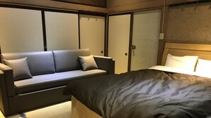 Quarto de hotel com cama, sofá e guarda-roupa.