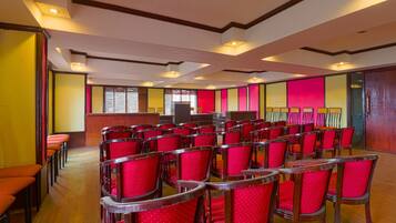 Uma sala de conferências com fileiras de cadeiras vermelhas, um púlpito e um palco.