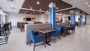 Restaurante moderno com cabines e mesas, teto de madeira e iluminação embutida.