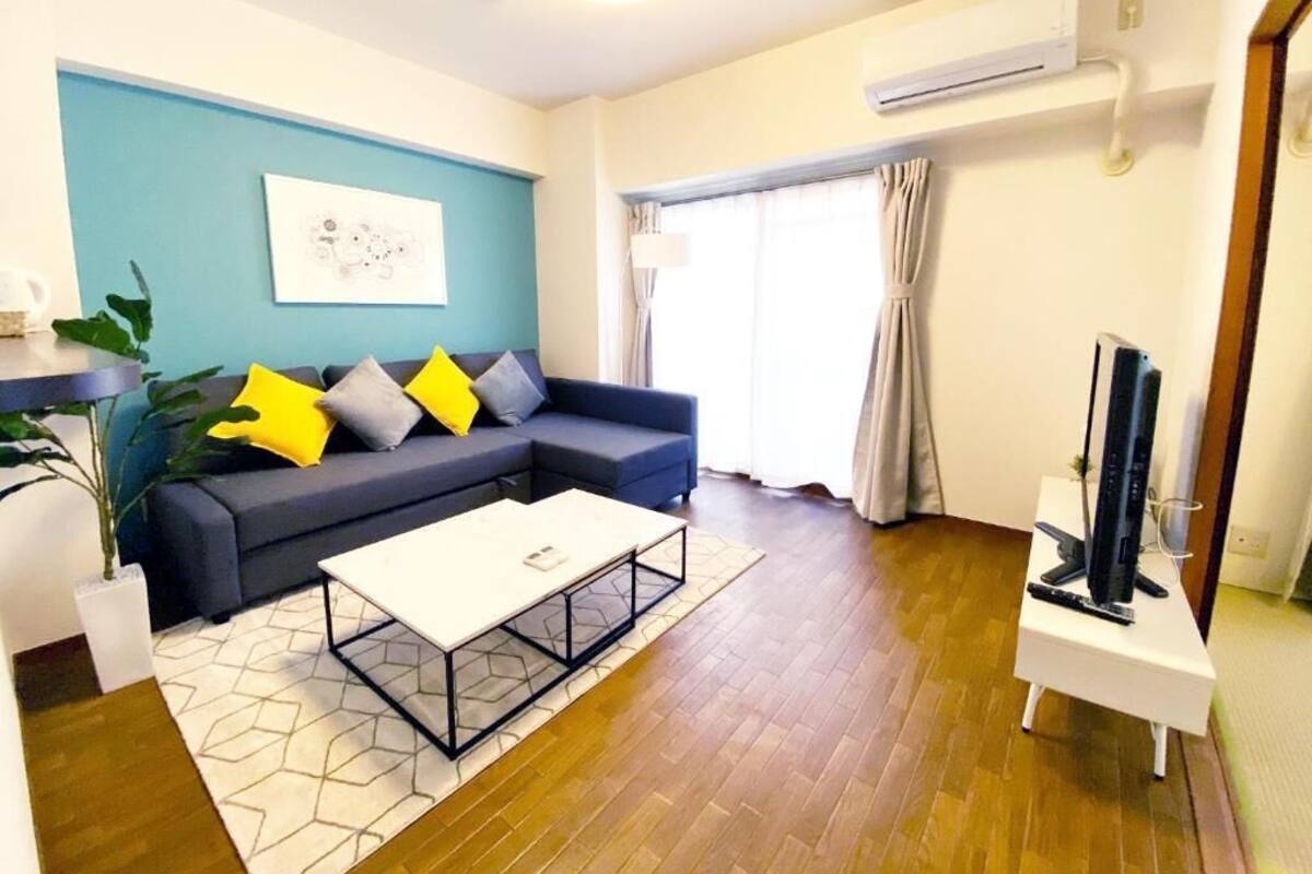 Uma sala de estar moderna com um sofá, mesa de centro e uma televisão de tela plana em um suporte.