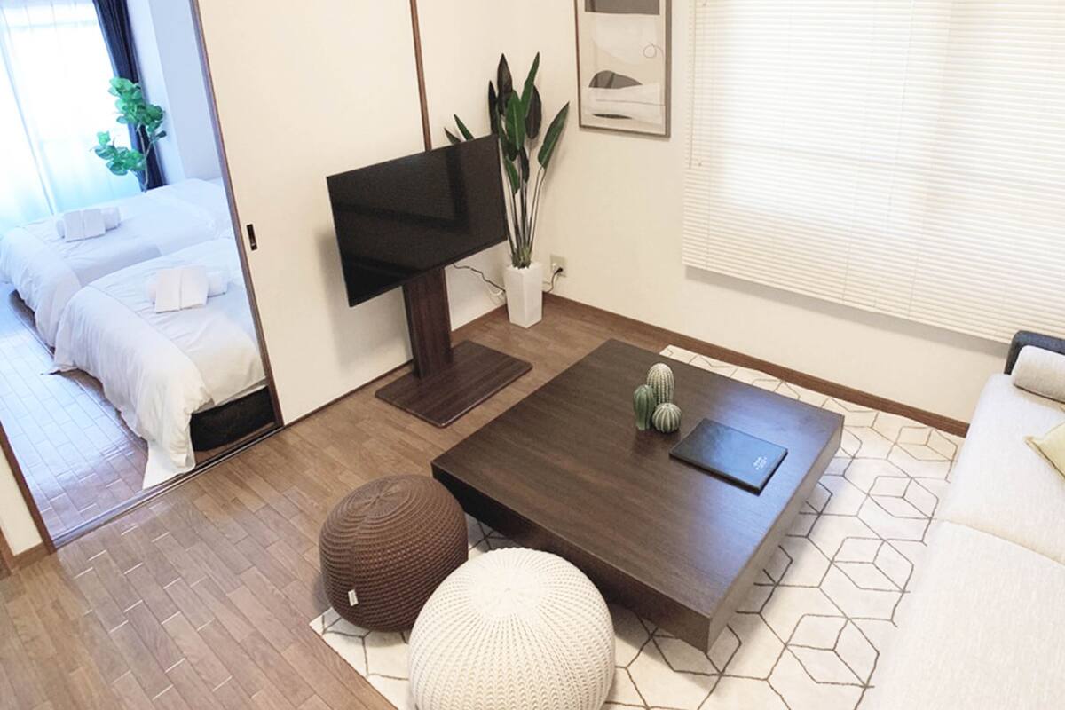 Uma sala de estar moderna com televisão de tela plana, mesa de centro, sofá e tapete estampado.