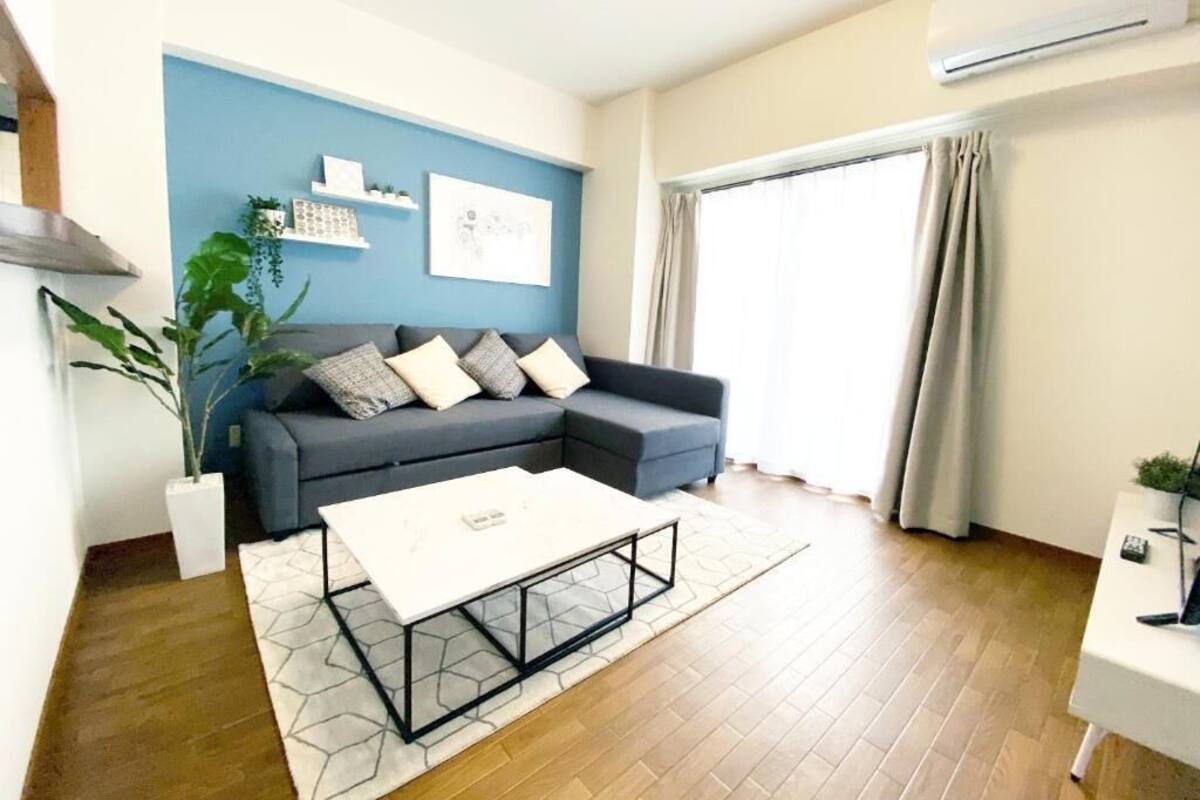 Uma sala de estar moderna com um sofá cinza, uma mesa de centro branca e uma parede azul de destaque.