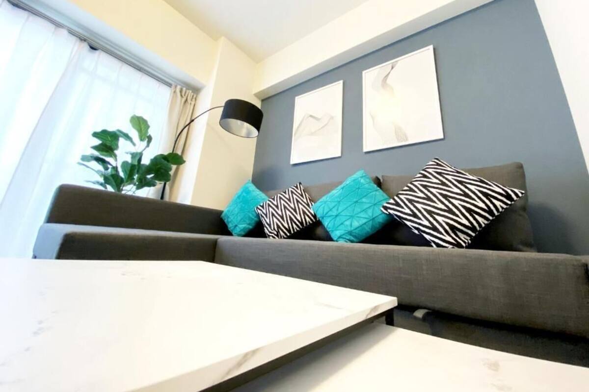 Uma sala de estar moderna com um sofá cinzento, almofadas estampadas e arte abstrata na parede.