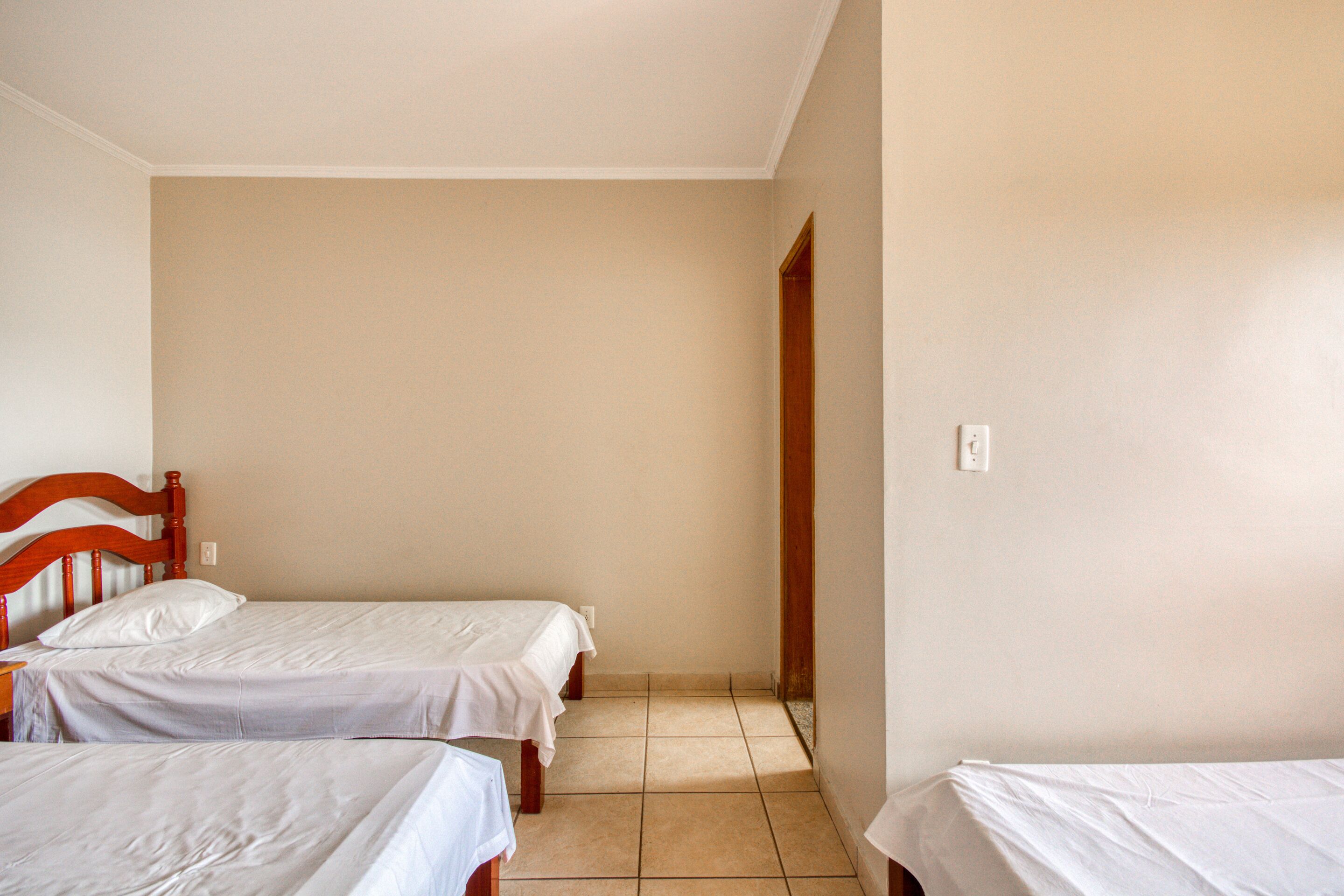 Quarto com duas camas de solteiro, cabeceiras de madeira e chão de azulejos.