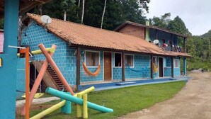 Um edifício de dois andares com telhado de cerâmica, varanda e um pequeno jardim com um parquinho.