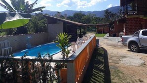 Quintal com piscina, móveis de área externa e uma caminhonete estacionada.