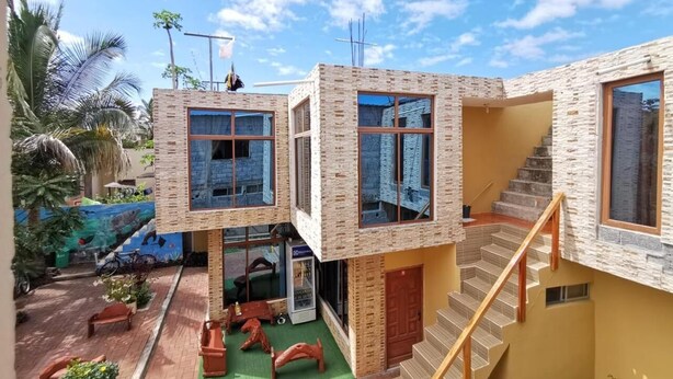 Uma casa com vários andares, com escada conectando os pisos, uma pequena área de estar ao ar livre e céu claro.