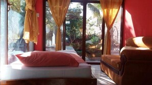Quarto com cama, sofá e amplas janelas com cortinas.