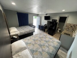 Quarto de hotel compacto com duas camas, uma escrivaninha, uma cadeira, uma televisão, um frigorífico e um micro-ondas.
