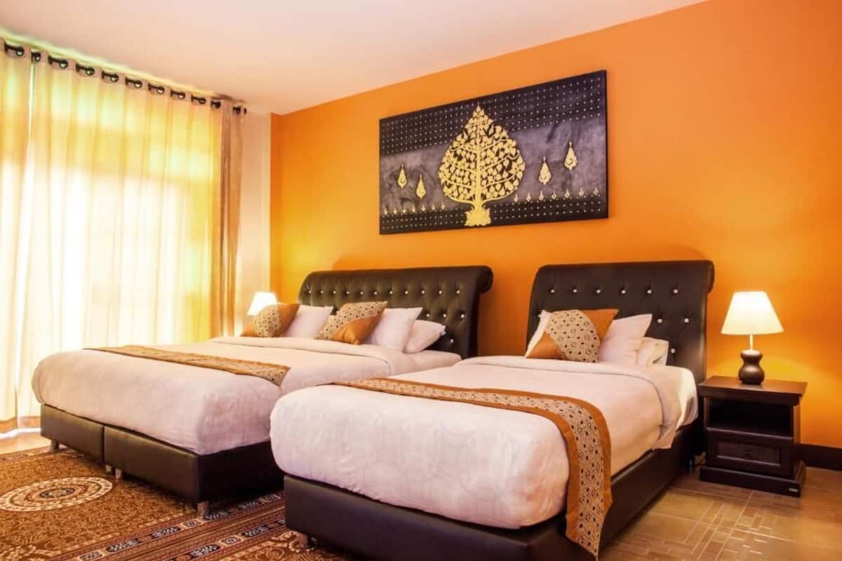 Quarto de hotel com duas camas, uma grande peça decorativa na parede e um tapete estampado.