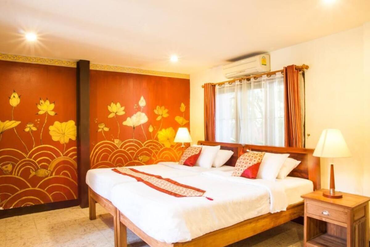 Quarto de hotel com cama, mesas de cabeceira, ar condicionado e um painel decorado com flores.