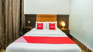 Quarto de hotel com uma cama grande, duas mesas de cabeceira, um painel de cabeceira de madeira e uma janela ampla.