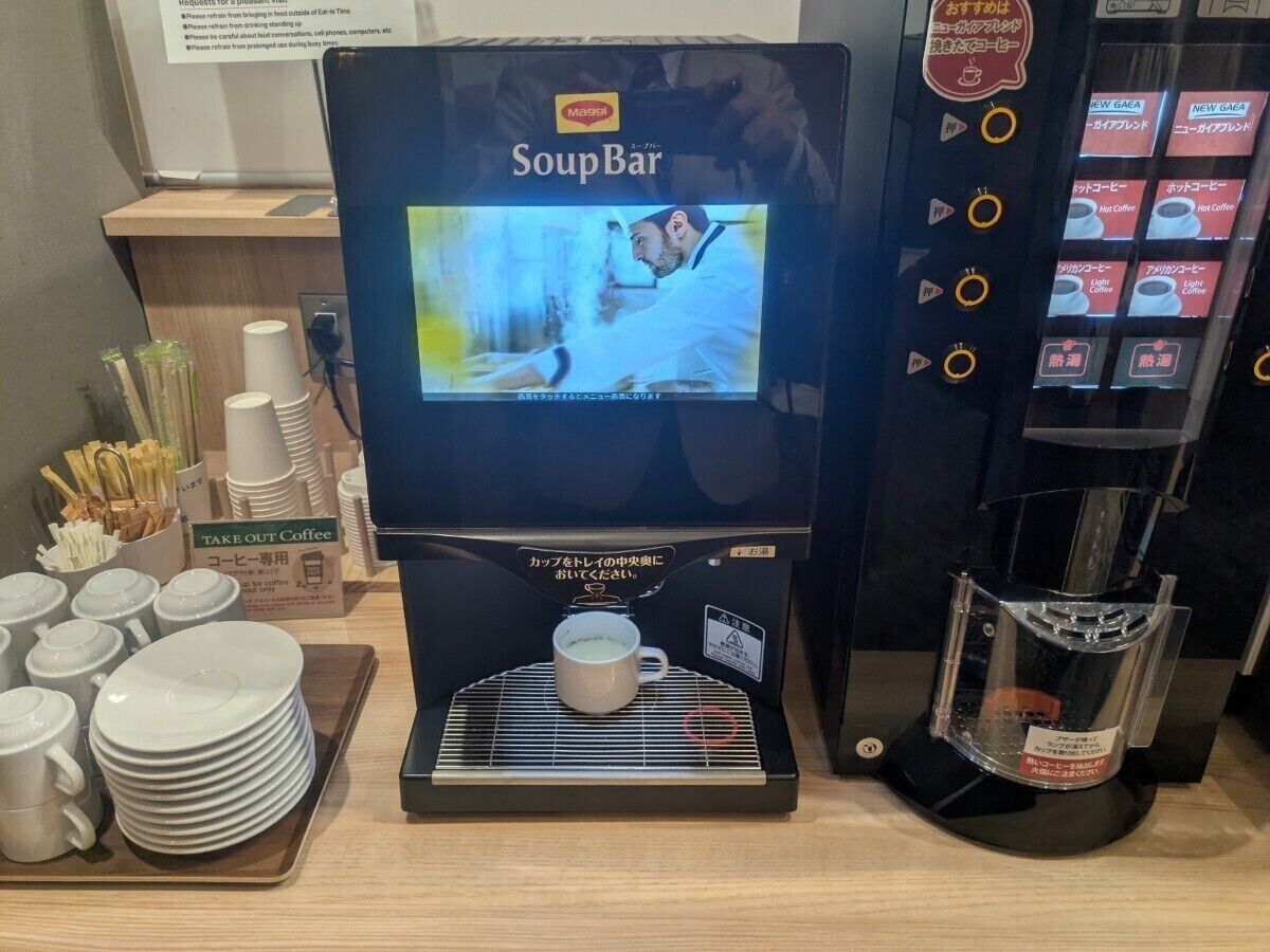 Máquina de café com visor digital, porta-copos e painel de menu.