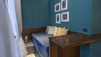 Quarto com uma cama, um banco de madeira e uma parede com quadros.
