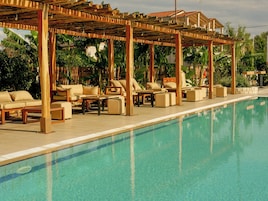Área de piscina com espreguiçadeiras e um pérgola.