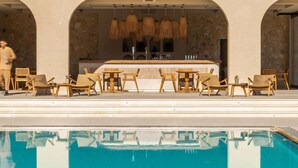 Uma área à beira da piscina com espreguiçadeiras e bar.